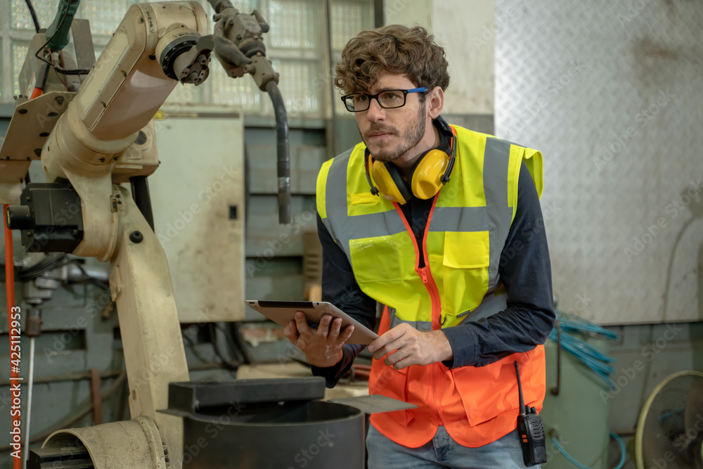 Engineer working and control robotic arm in manufacturing workshop ...