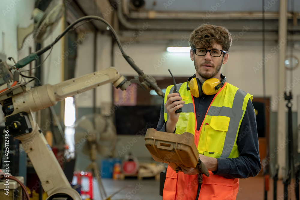 Engineer working and control robotic arm in manufacturing workshop ...