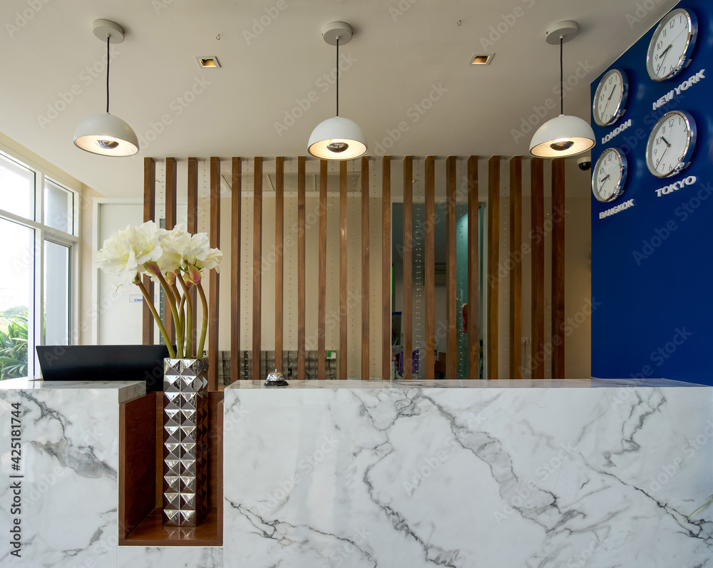 A long white marble reception counter located in the hotel lobby. The ...