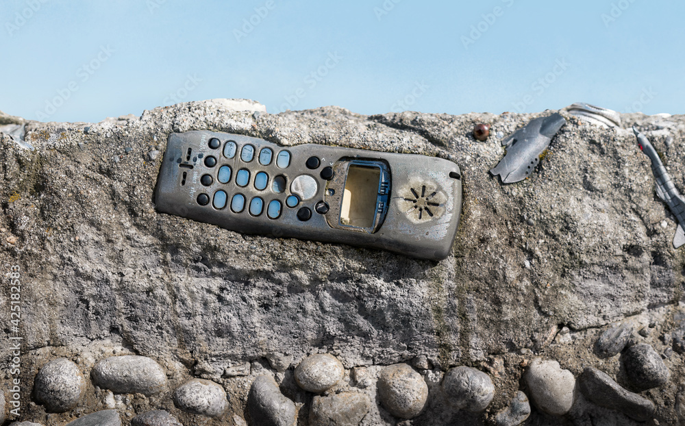 Old phone embedded in concrete layer with defocused landscape ...