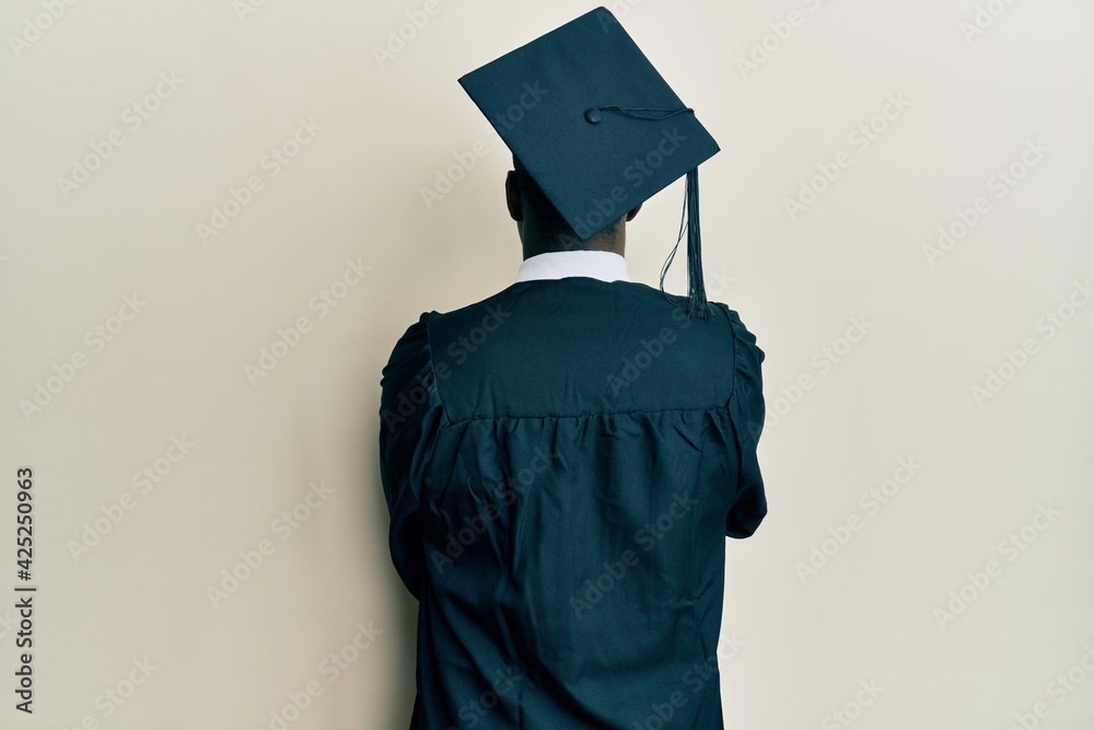 Handsome black man wearing graduation cap and ceremony robe standing ...