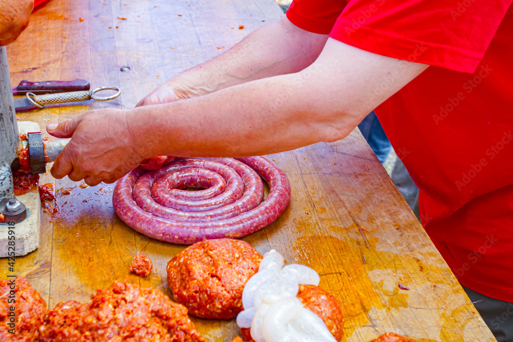 Butcher is stuffing pig intestine with minced meat to make sausages ...