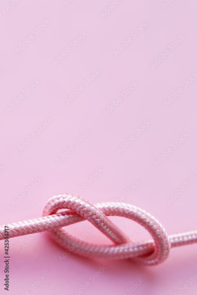Vertical pastel pink background picture with a rope. A concept for ...