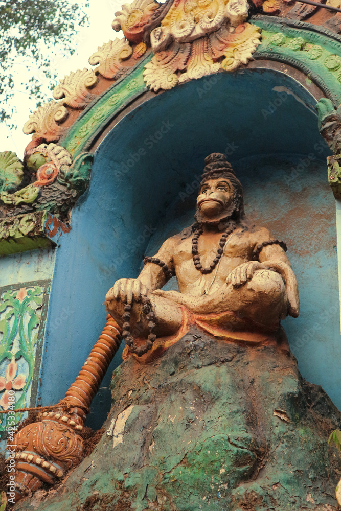 An old sculpture on the wall of a Hindu temple. Hanuman sits in the ...