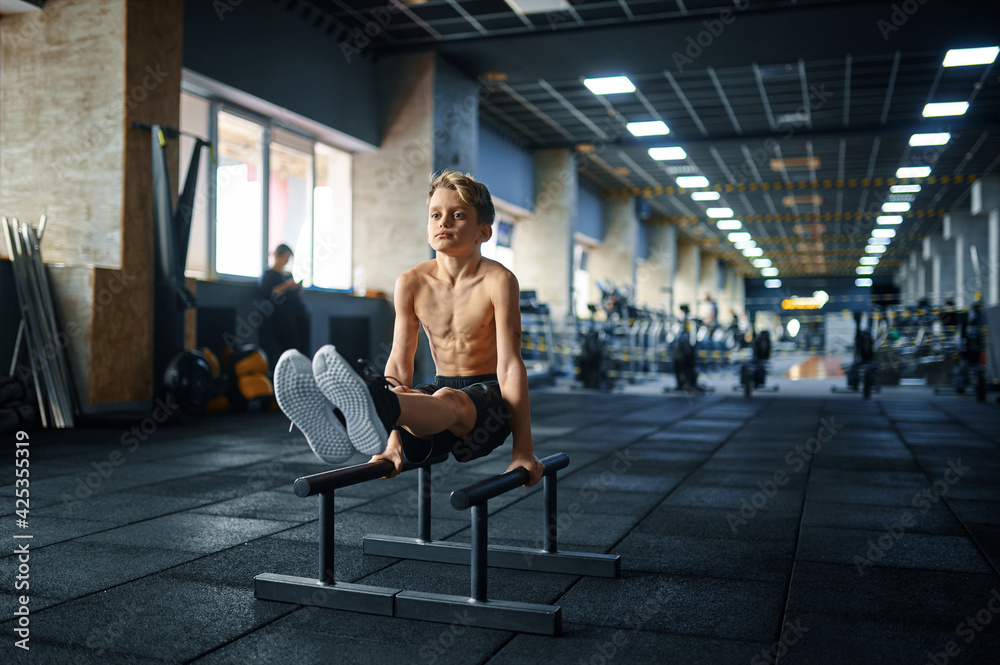 Boy doing ABS exercise on uneven bars in gym Stock Photo | Adobe Stock
