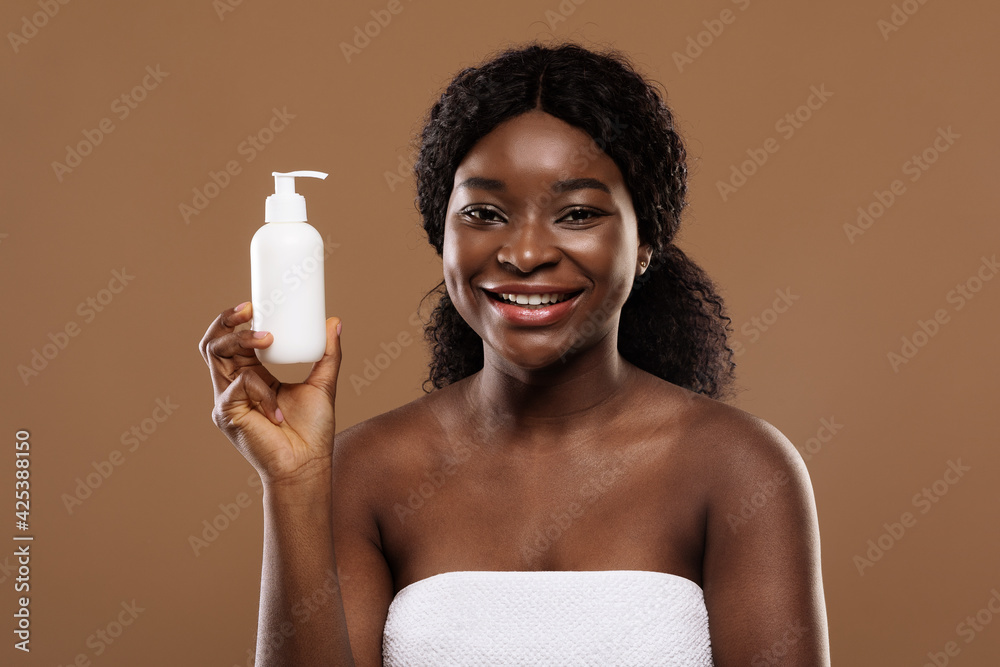 Body Skin Moisturising. Attractive Black Female In Towel Holding Bottle ...