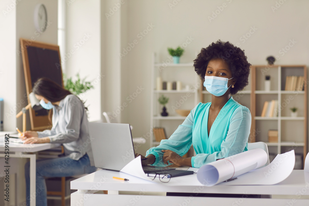Return to workplace after coronavirus pandemic lockdown. Portrait of black woman in face mask ...