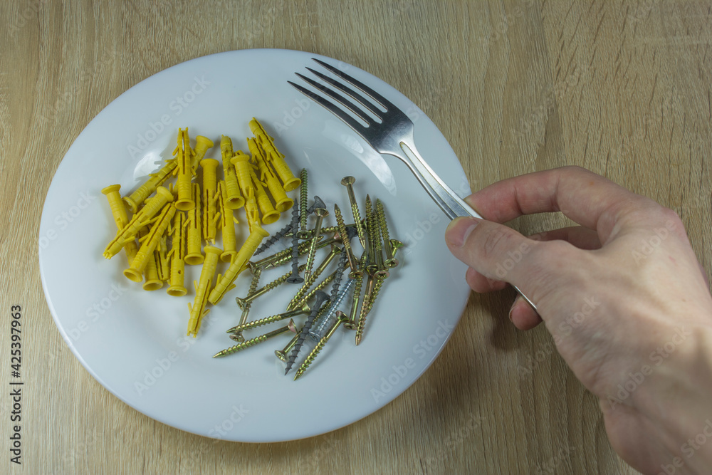 screws and dowels on a plate imitating macaroni and a hand holding a ...