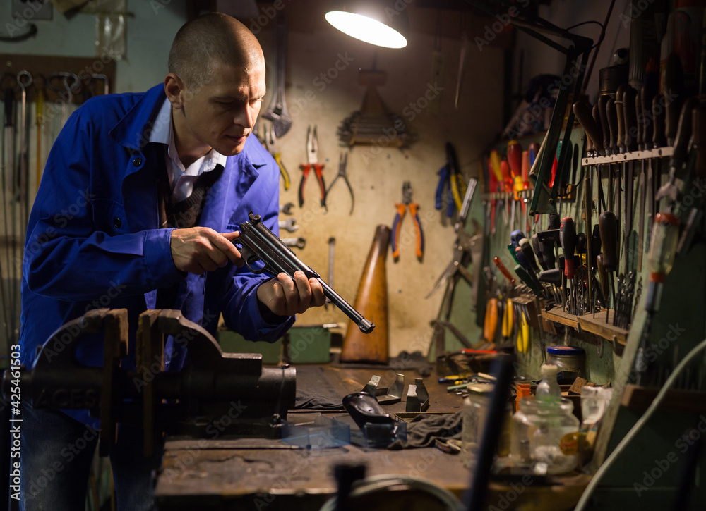 Gunsmith disassembles and repairs pistol in a weapons workshop Stock ...