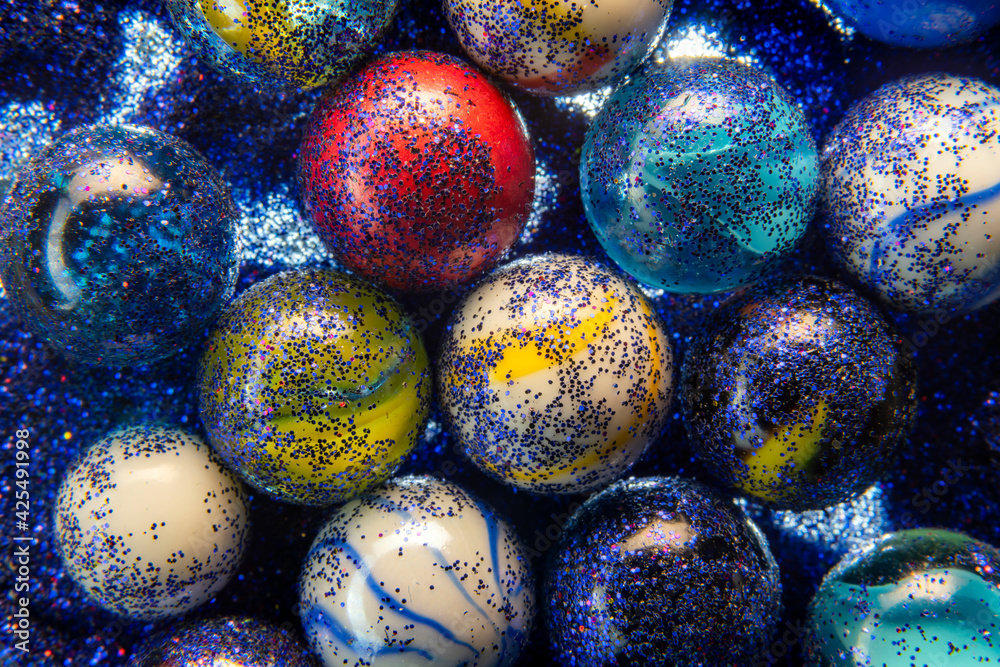Macro photography of a bunch of marbles with glitters. The marbles have ...