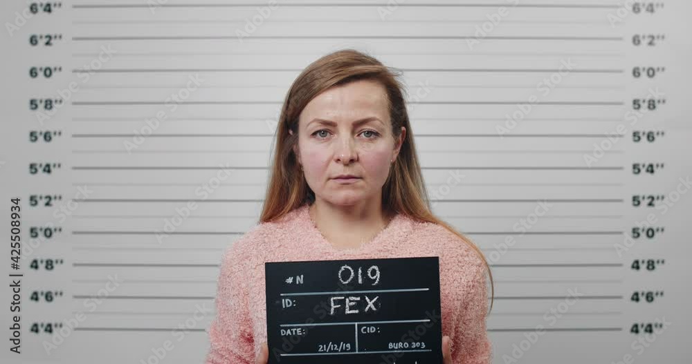 Video „Mugshot of young arrested woman holding sign for photo in police ...