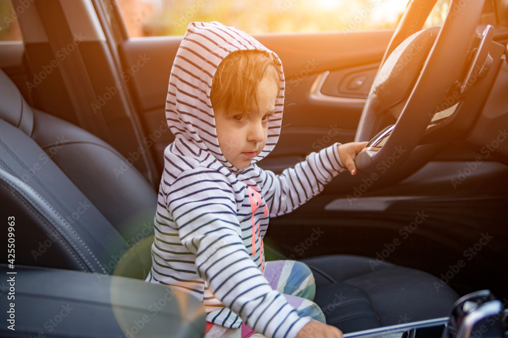 cute toddler plays driver in parents modern car. adorable child explore ...