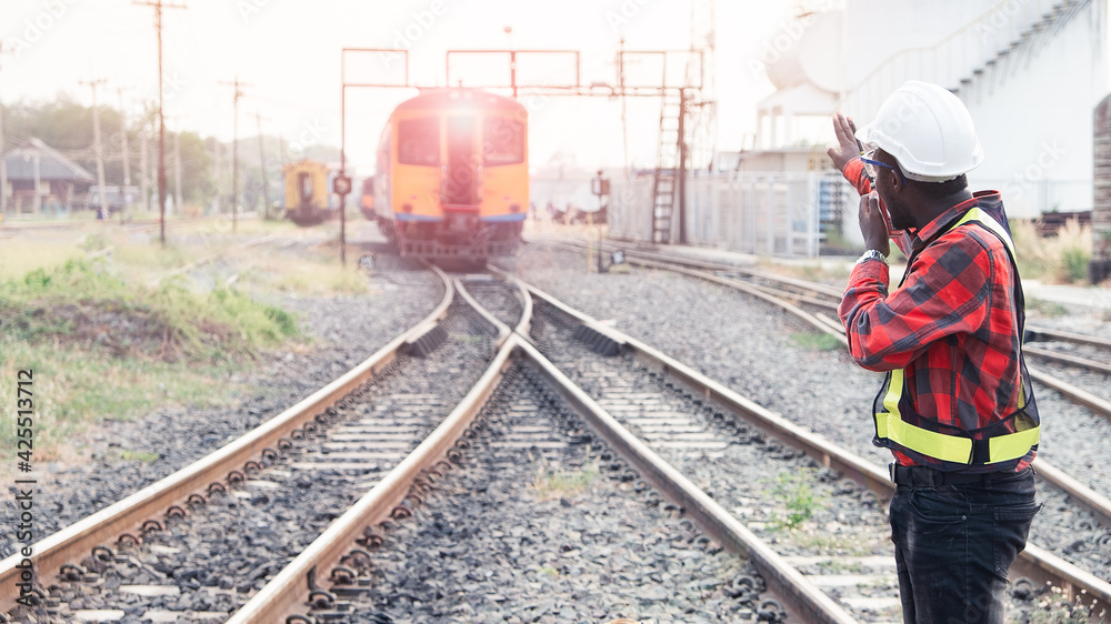 African engineer raised a hand to control a the train on railway with ...