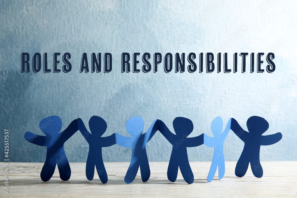 Roles and Responsibilities. Paper people holding hands on wooden table ... Roles and Responsibilities. Paper people holding hands on wooden table ...