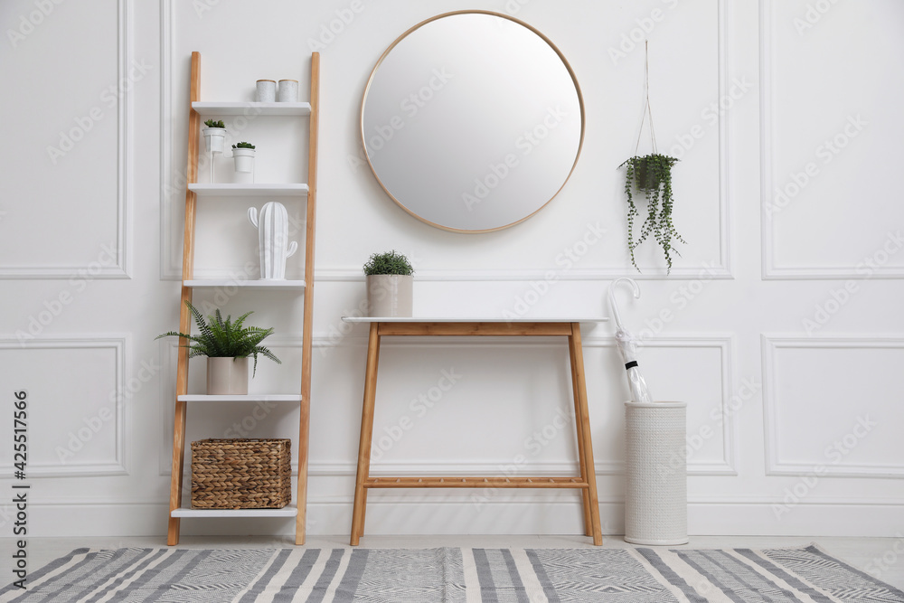 Console table with shelving unit and mirror on white wall in hallway ...