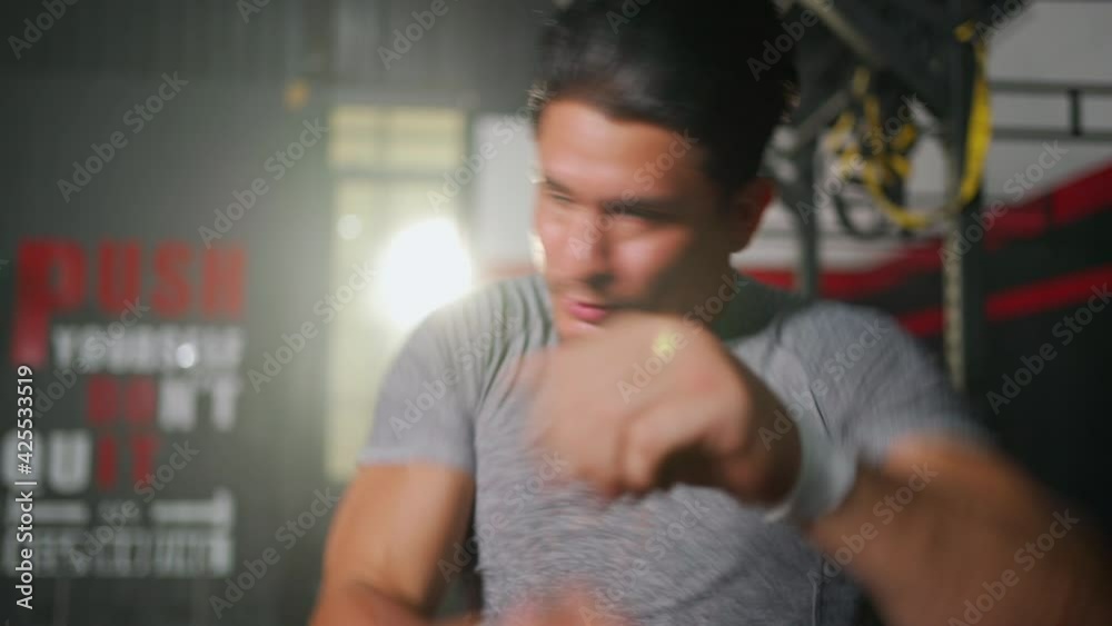 Handsome fighter man punch out in front of camera in the fitness gym ...