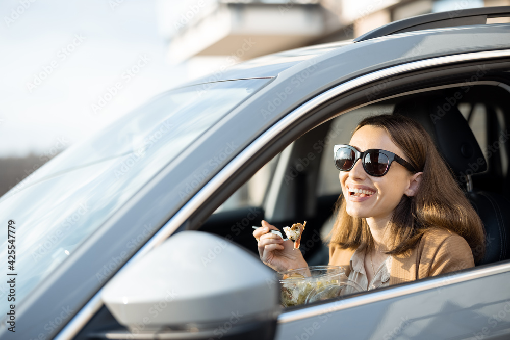 Beautiful woman eating heathy salad in the car. Received a food order ...
