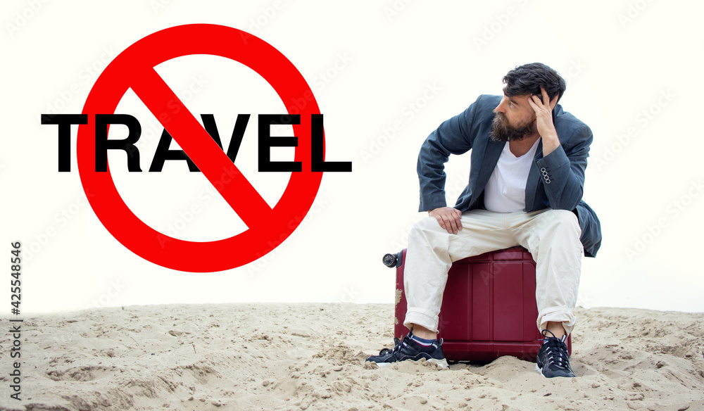 Concept - no travel, forbidden. Sad man sits on a red suitcase. Male ...