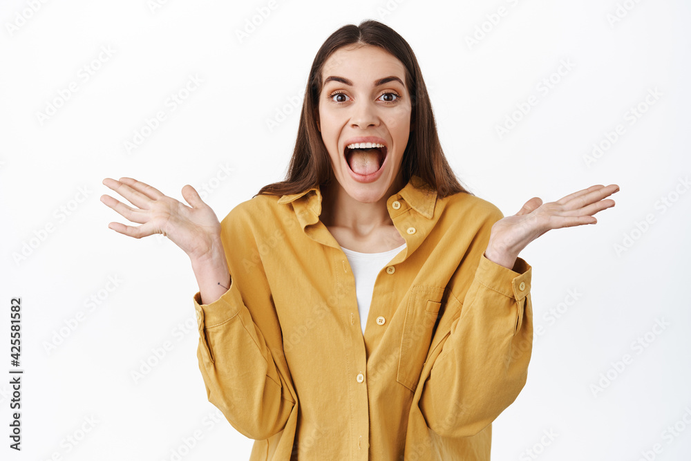 Attractive caucasian woman scream from amazement and surprise, spread ...