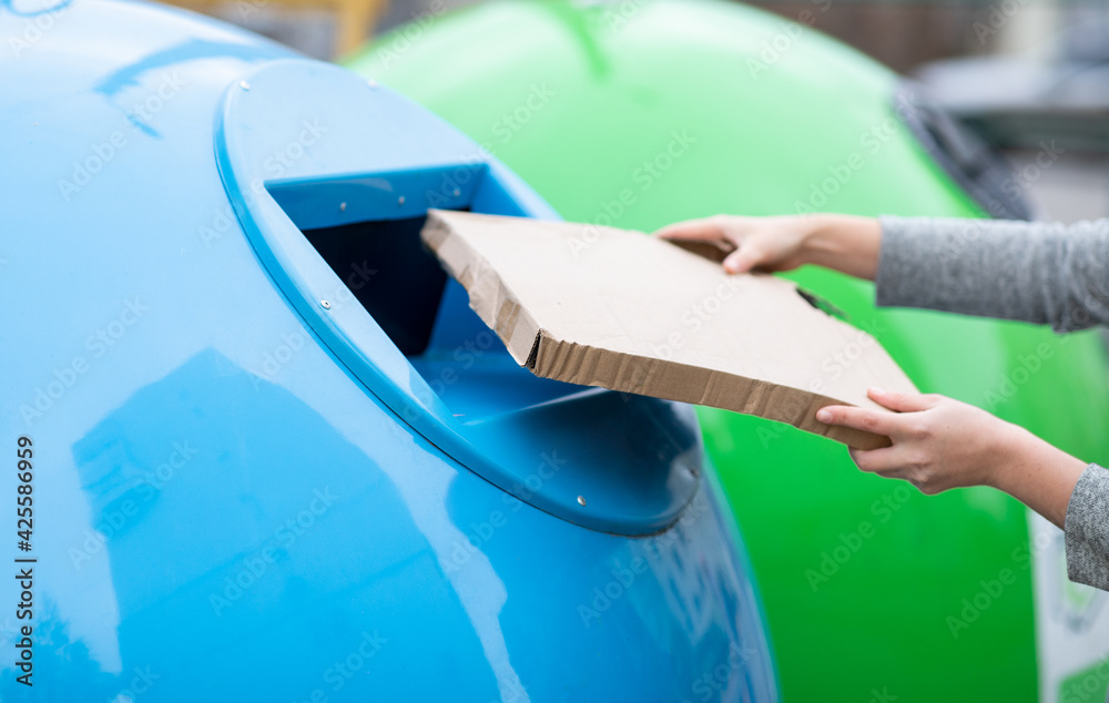 Waste Sorting. Female throwing cardboard box into blue recycle bin ...