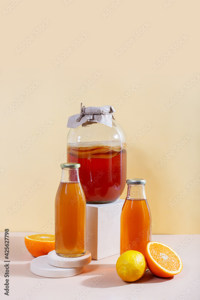 Glass gar with komucha tea, citrus fruits and two bottles with ready ...