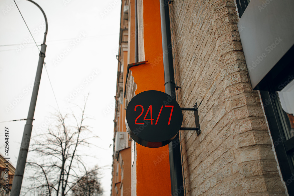 round sign on the facade. advertising about round-the-clock work ...