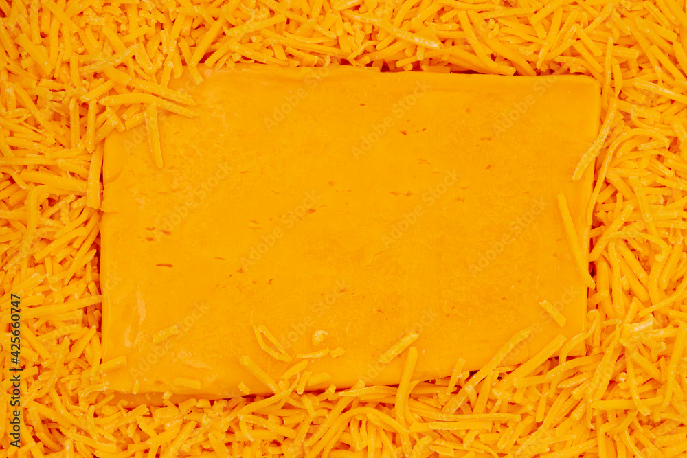 Block of cheese on shredded cheddar cheese background Stock Photo ...