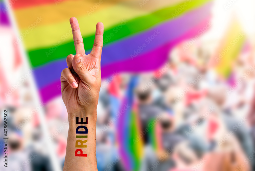 Supporting hand makes peace sign in front of a rainbow flag flying on ...