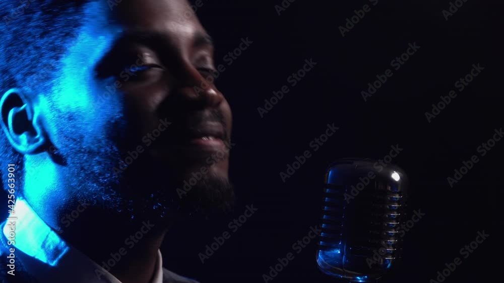 African American man in a stylish suit sings a song into a retro ...