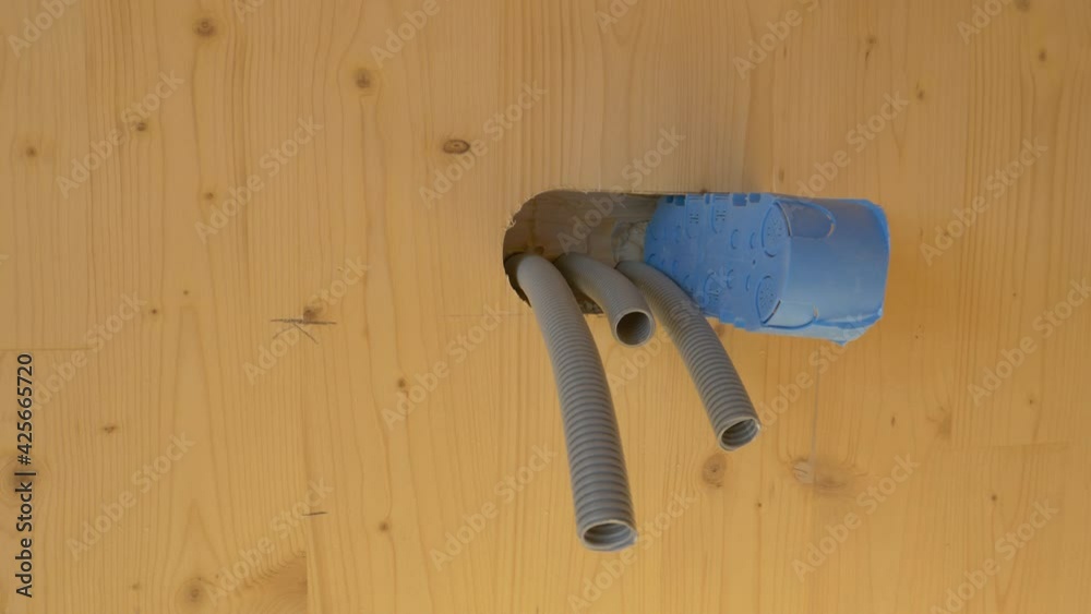 CLOSE UP: Corrugated conduits and blue socket box protrude out of a ...