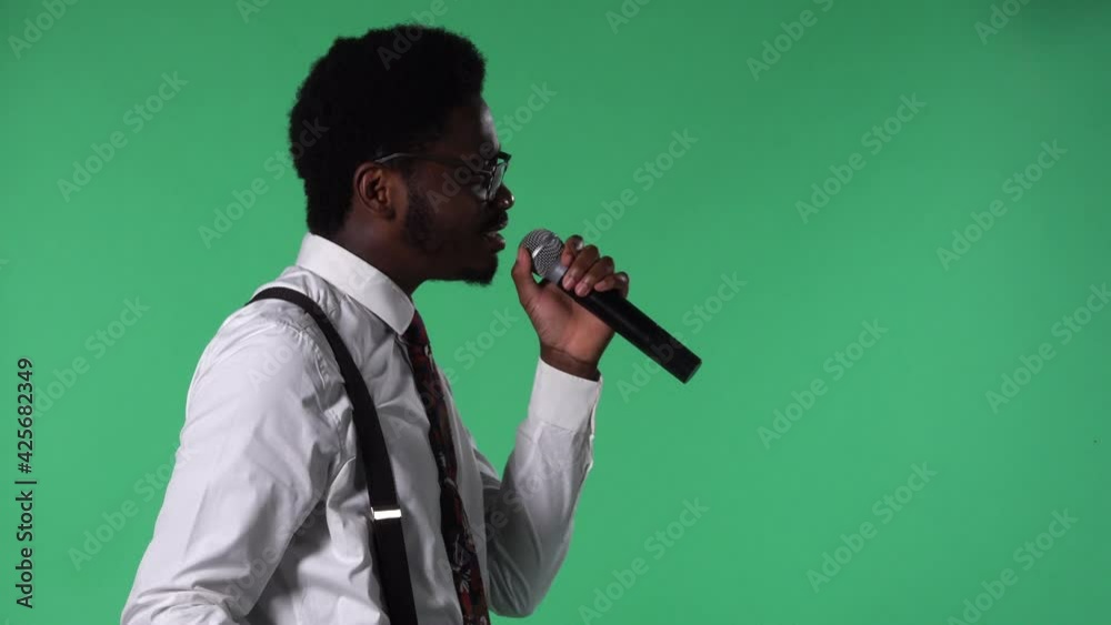 Portrait young African American man singing happily into microphone and ...
