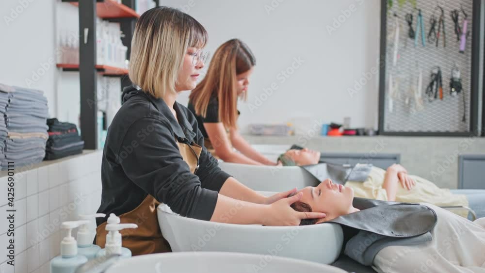 Professional hairdresser giving hair wash and massage in beauty salon ...