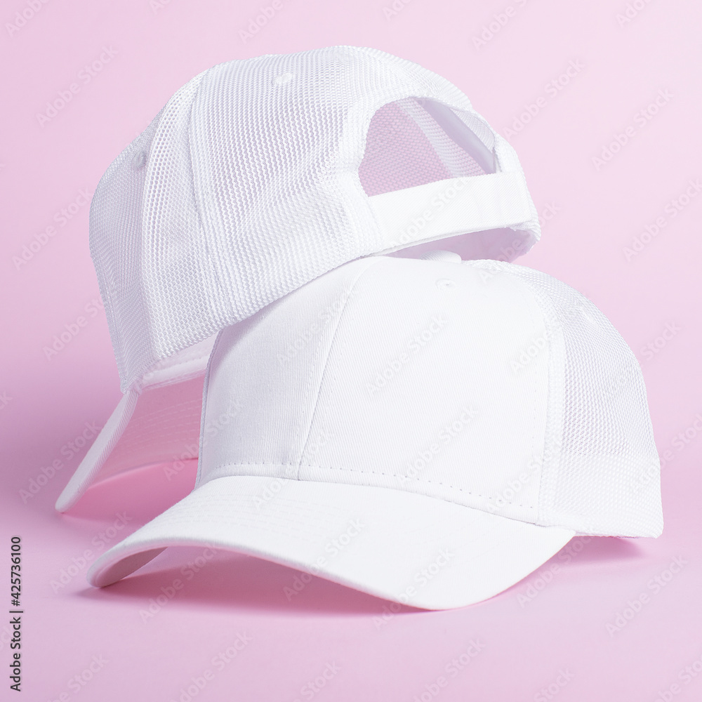 Two white baseball caps isolated on a pink background, front and back ...
