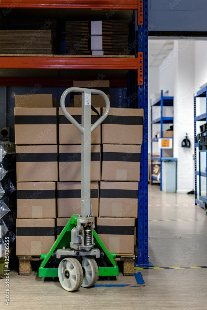 A pallet stacked with boxes ready to be shipped out. A pallet truck is ...