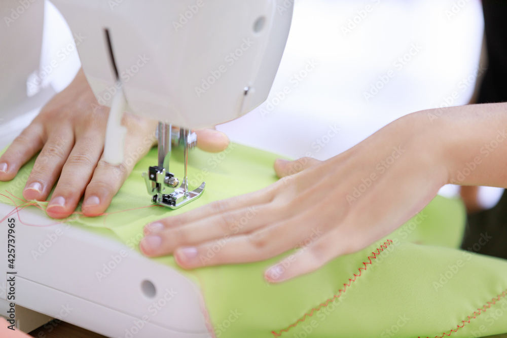 Selective focus on hand. Woman seamstress sitting and sews. Lady makes ...