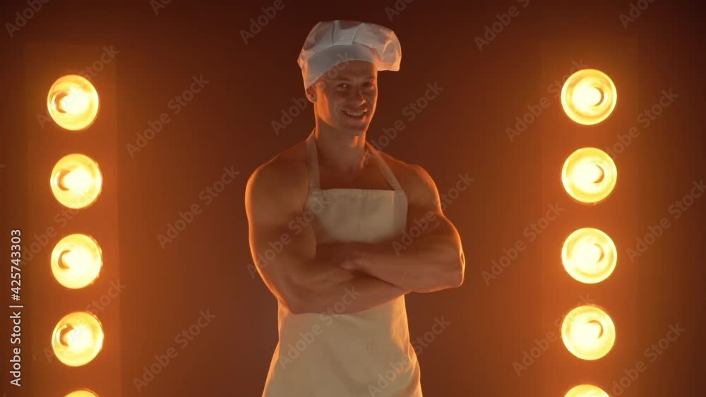 Portrait of muscular chef wearing white apron and chef hat, showing ...