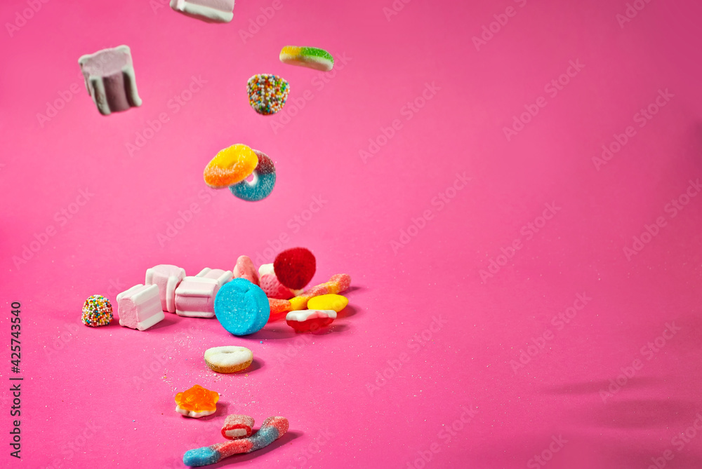 Many colorful candies fall on a pink background. Sweets close up. The ...