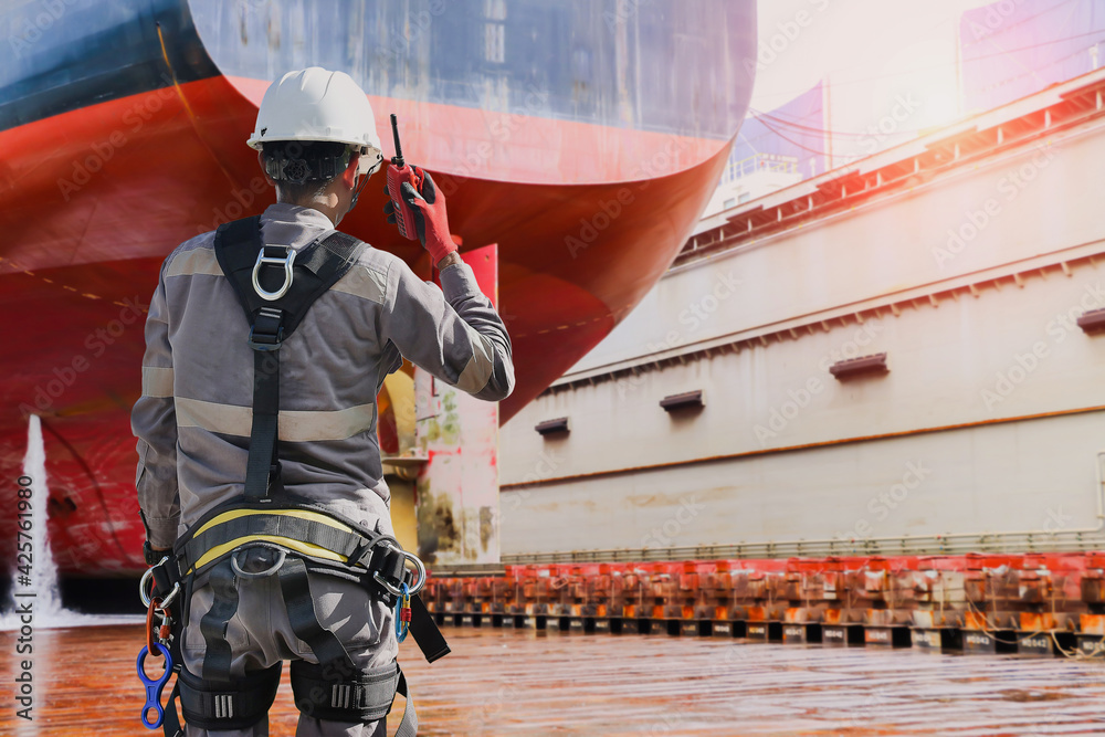 Workers wearing full safety harness and hand holding communication ...