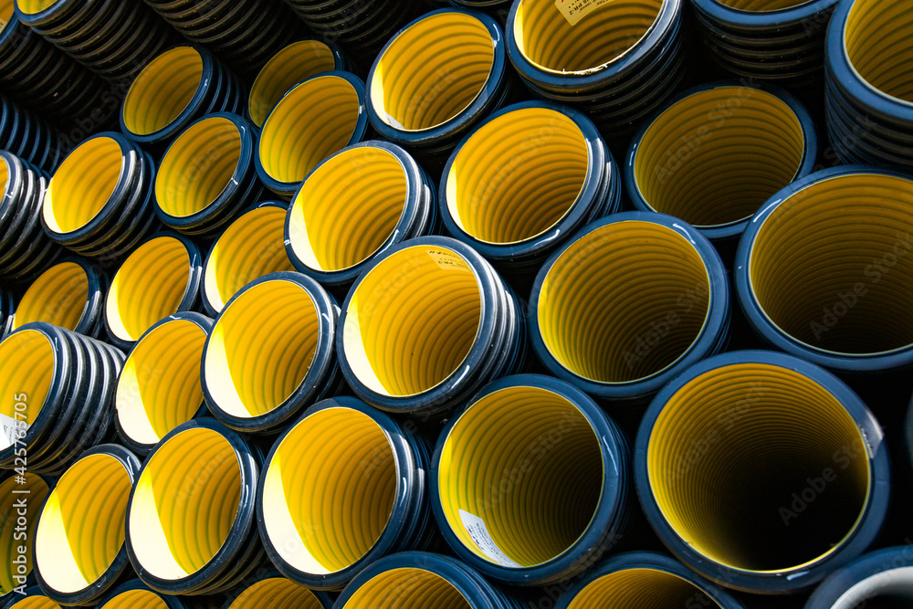 Plastic pipes production plant warehouse. Yellow PVC channelled pipes ...