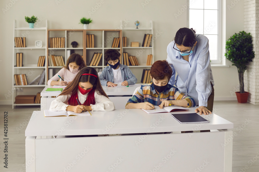 Coronavirus safety measures in class. Students and teacher wearing ...