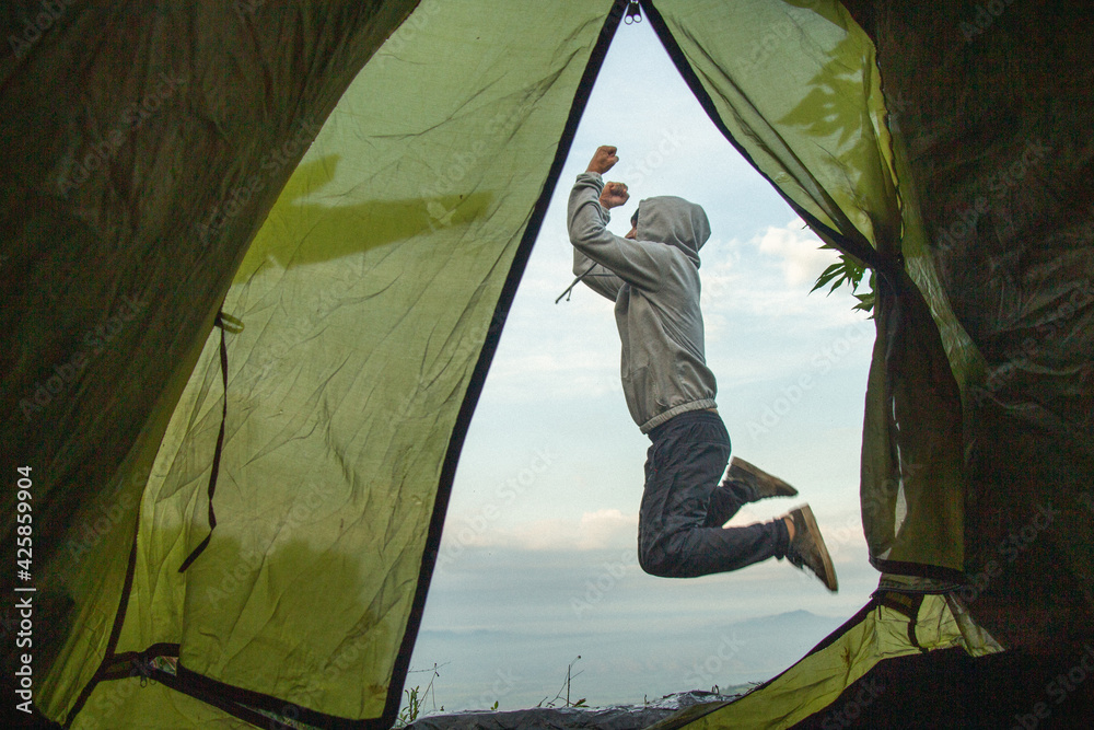 Hombre acampando en una carpa y dando un salto de alegría fuera de su ...