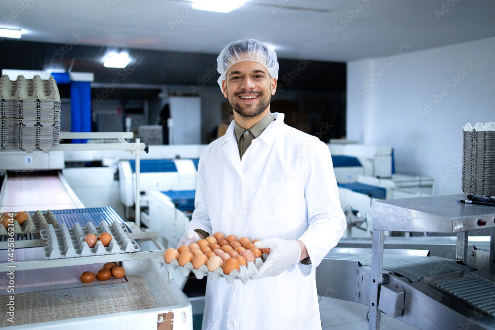 Portrait of an egg farm worker holding cardboard crate with fresh eggs ...