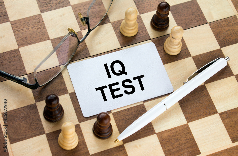 Business card with text Iq Test on a chess board with pen and ...