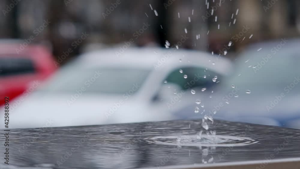 Slow motion close up raindrops are falling into big puddle on asphalt ...