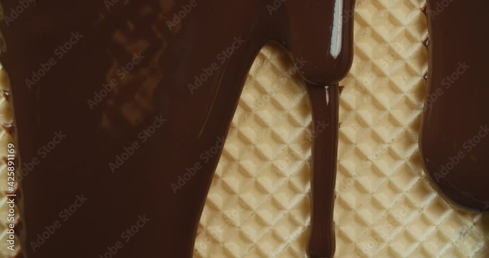 Close-up macro shot hot melted liquid chocolate flows over wafer ...
