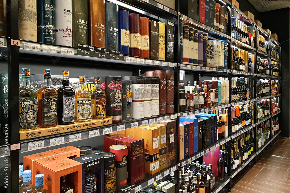 An assortment of wine and hard liquor bottles stacked neatly on store ...
