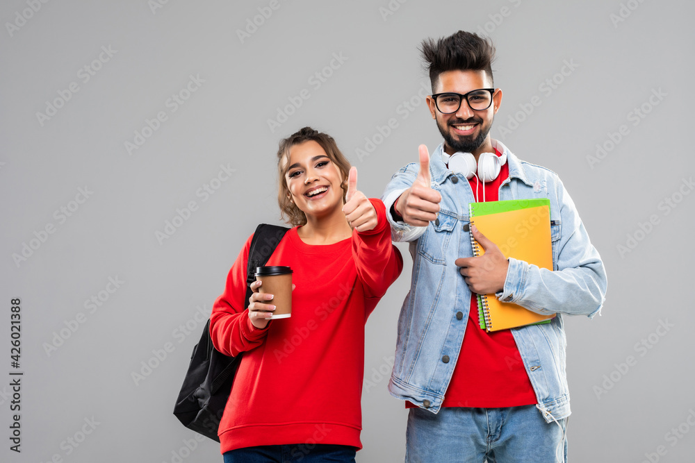Young indian students with backpacks and books making thumb up gestures ...