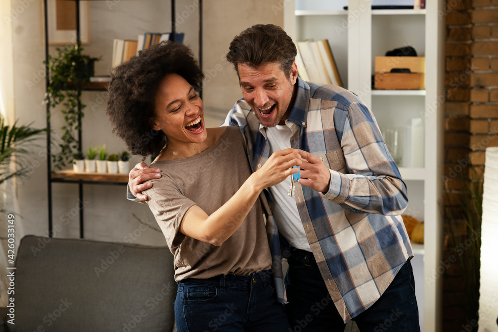 Foto de Smiling couple is taking keys from their new apartment. Husband ...