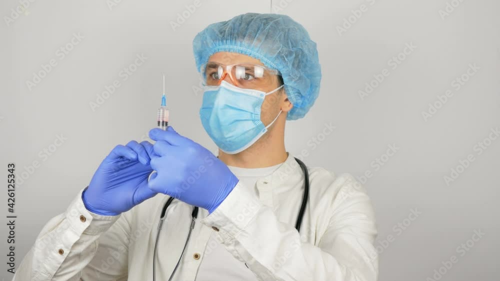 A young handsome doctor prepares for vaccination, prepares a syringe ...