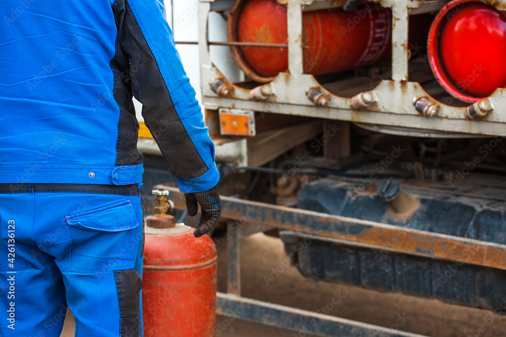 Male industrial worker puts a gas cylinder into a gas machine ...
